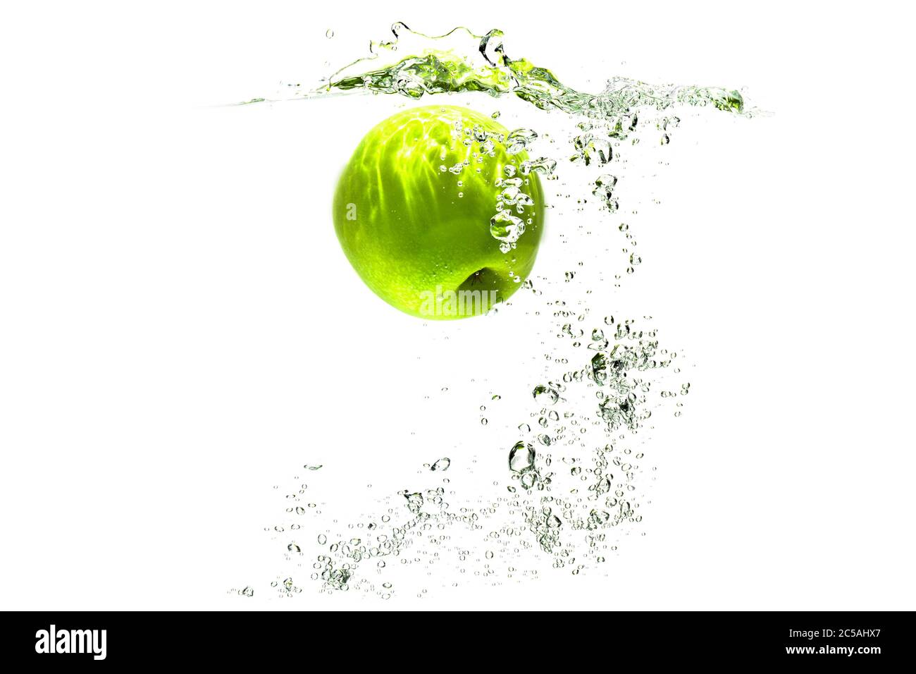 one green apple falling into water on a white background with splashes ...