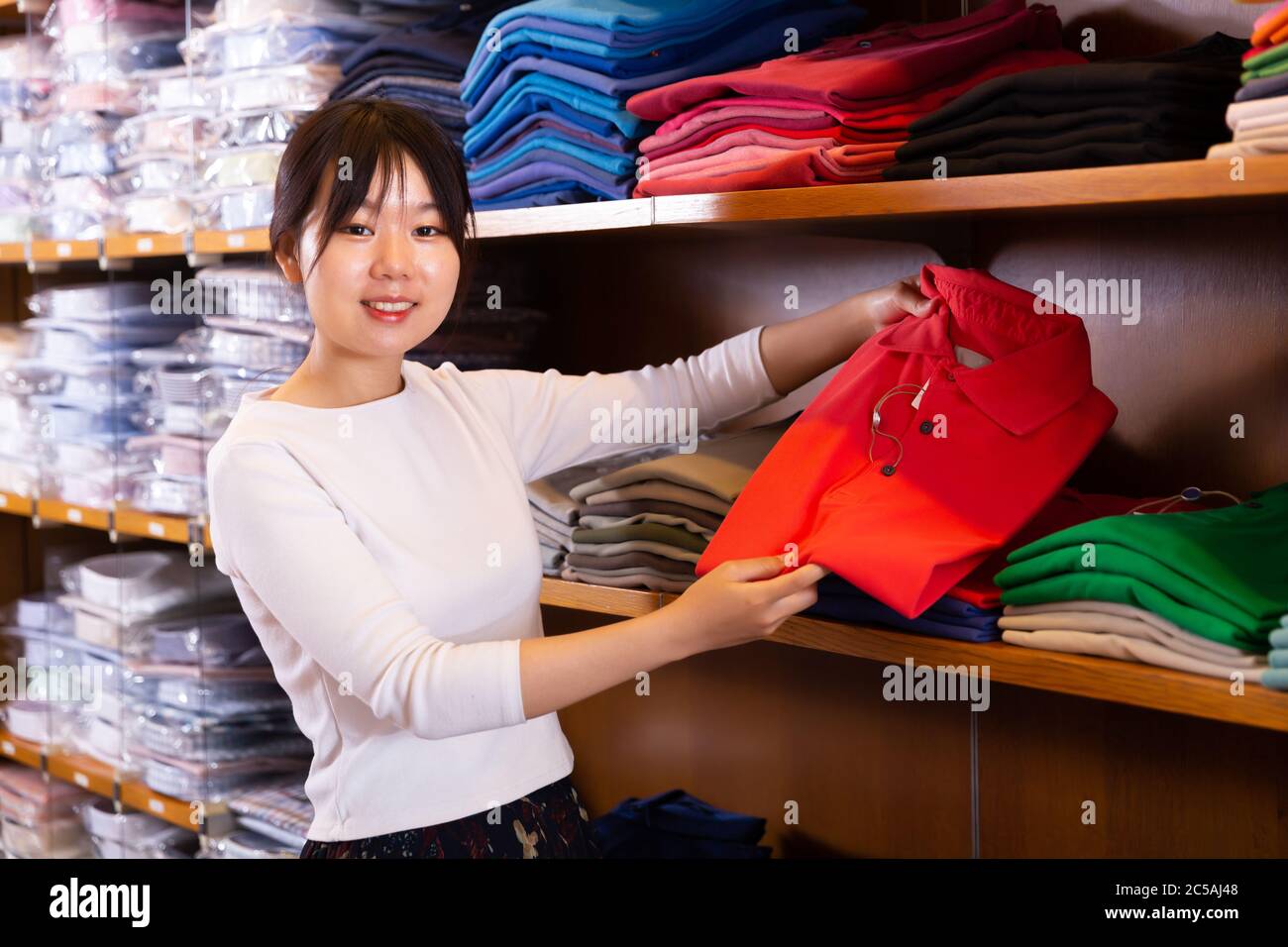 Chinese female shopping assistant offering various shirt in men’s ...