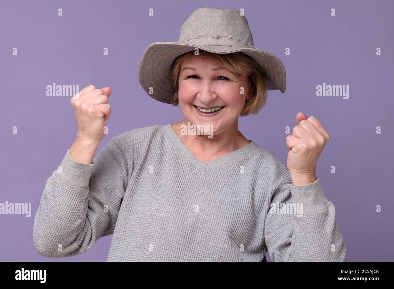 Happy senior caucasian woman in summer hat pumping fists up, celebrate ...