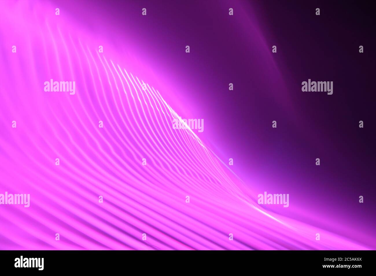 Horizontal shot of intersecting refracted pink light layers on a black ...