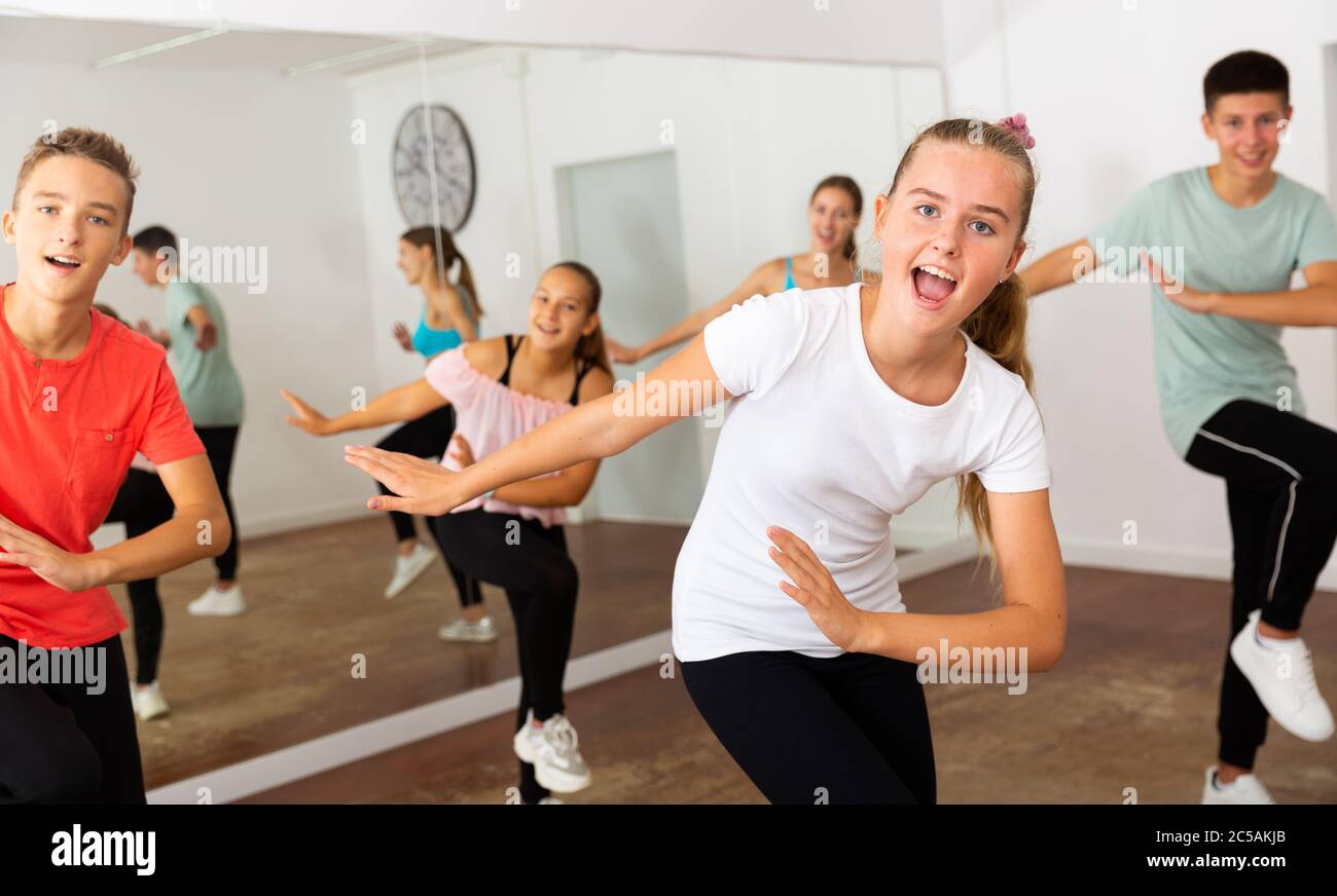 Teenage girl dancer practicing active vigorous dance with group in ...