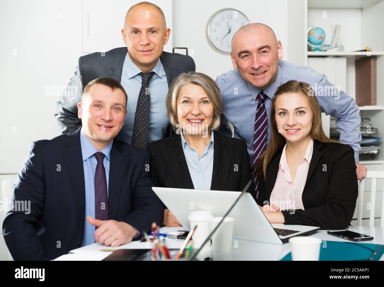 Smiling professional business team of five posing at office delighted ...