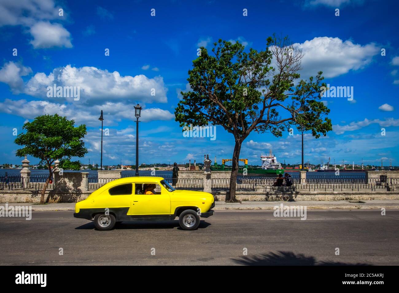 Havana, Cuba, July 2019, an old yellow car driving pass on the Malecon ...