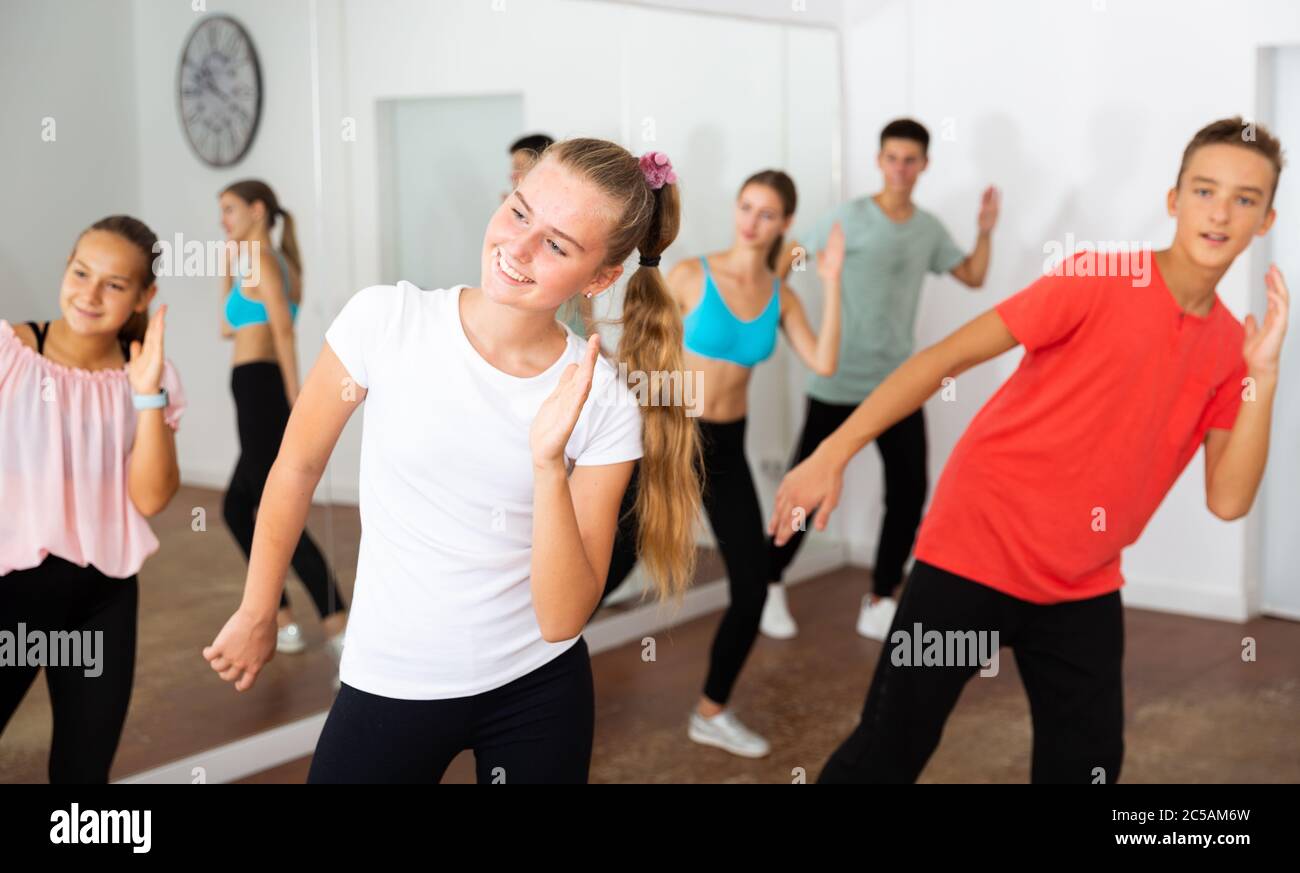 Teenage girl dancer practicing active vigorous dance with group in ...