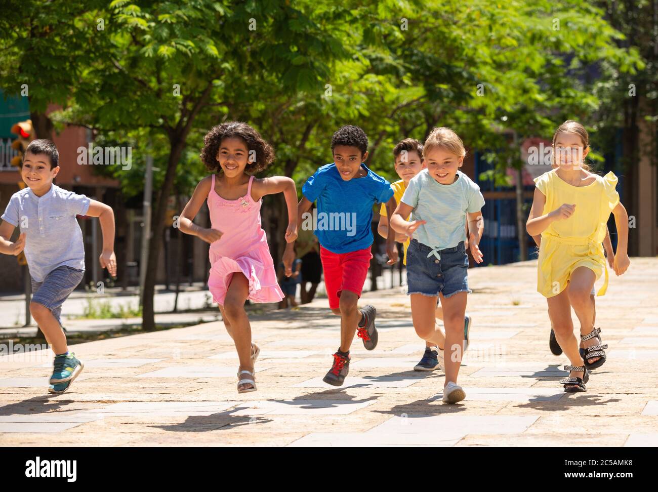 Team of positive kids running in race in the street and laughing ...