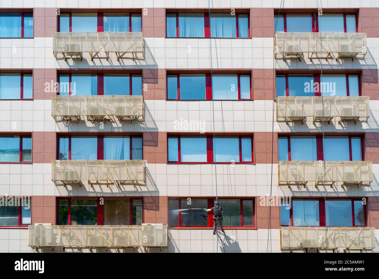 Worker washes windows in an office building. Washing the facade of an ...