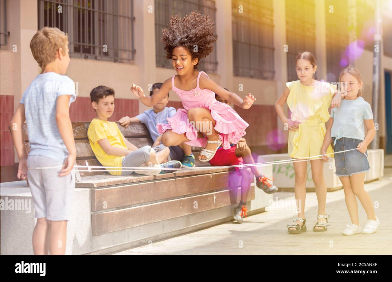 Happy smiling little friends playing with chinese jumping rope at ...