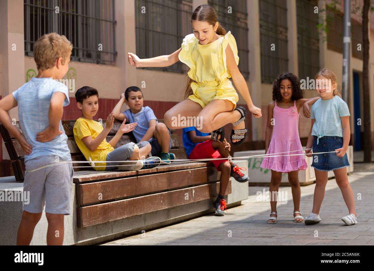 Energetic kids playing and skipping on elastic jumping rope in european ...