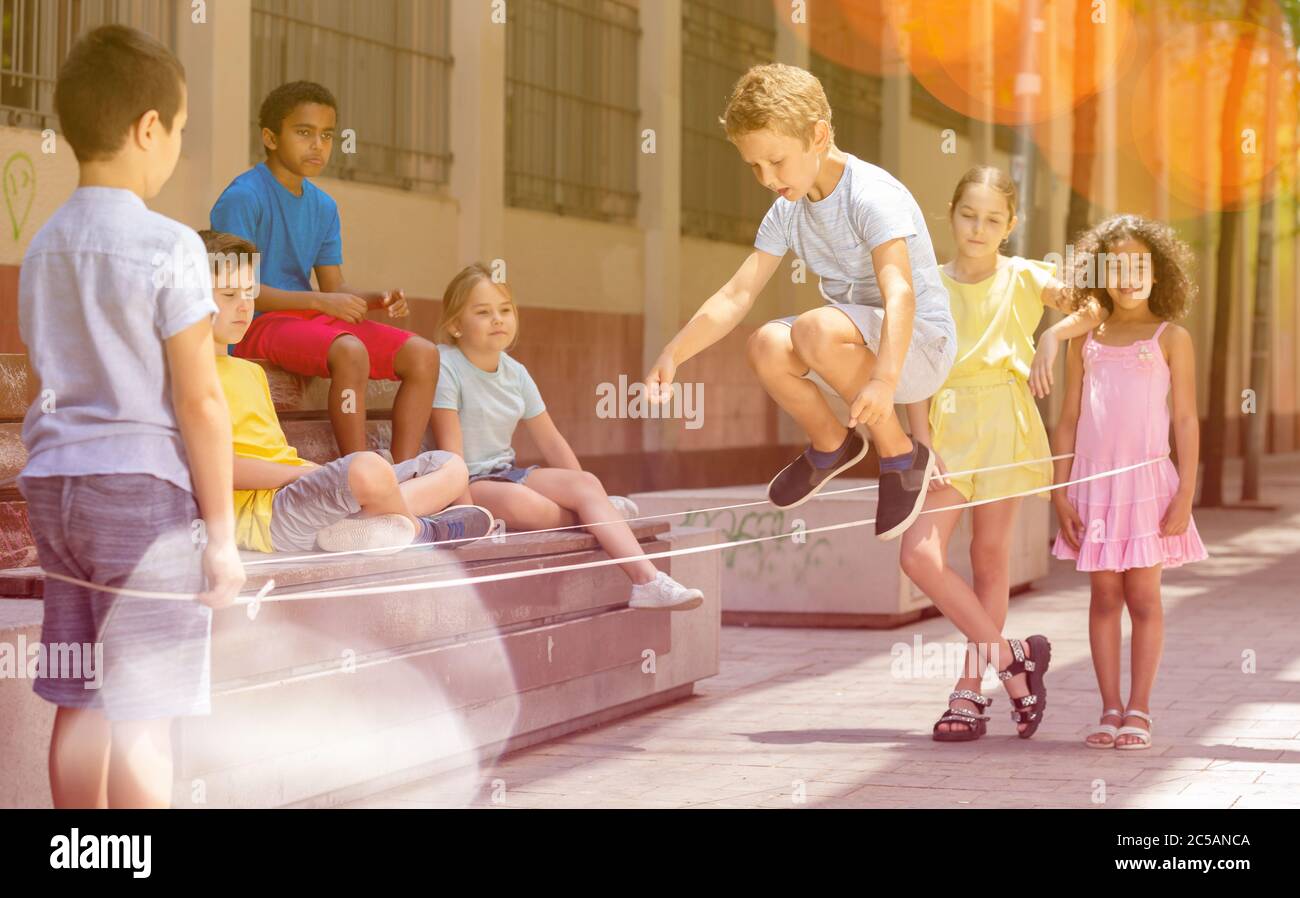 Smiling kids skipping on jumping elastic rope in european yard Stock ...
