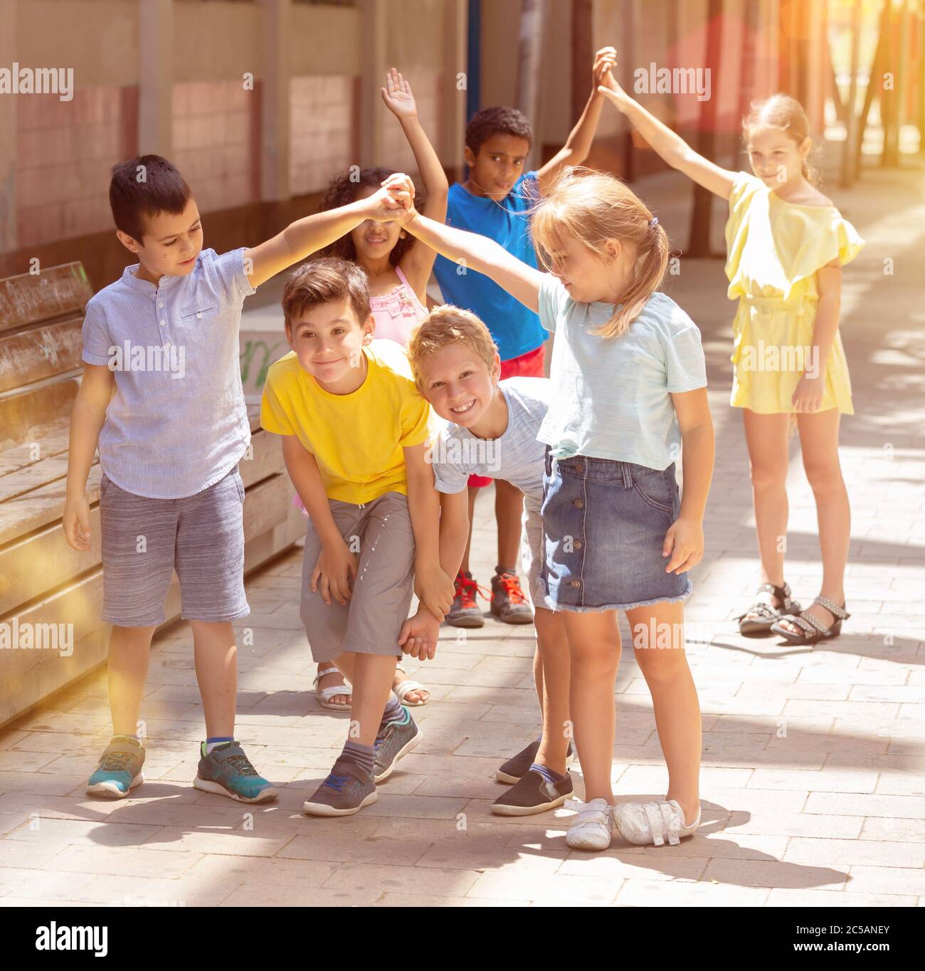 Group of positive schoolchildren holding hands up and playing together ... Group of positive schoolchildren holding hands up and playing together ...