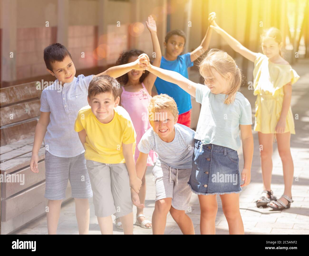 Group of positive schoolchildren holding hands up and playing together ... Group of positive schoolchildren holding hands up and playing together ...