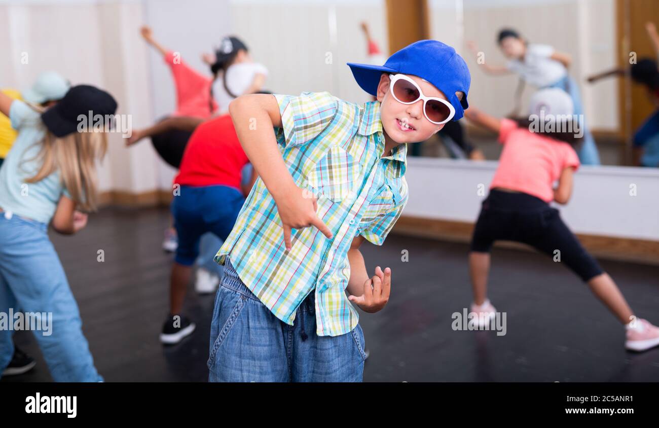 Portrait of emotional boy doing hip hop movements during group class in ...