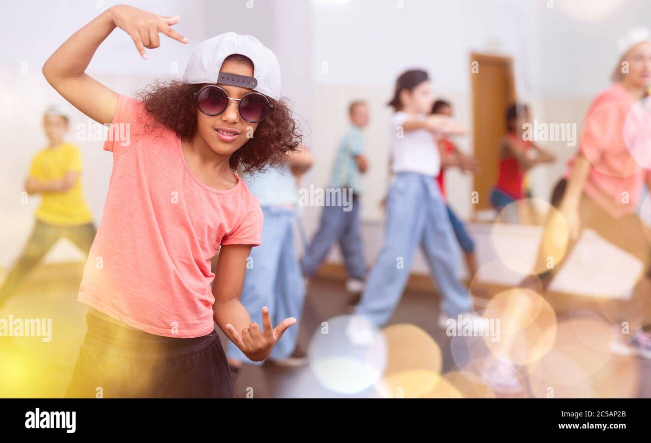 Portrait of emotional african girl doing hip hop movements during group ...