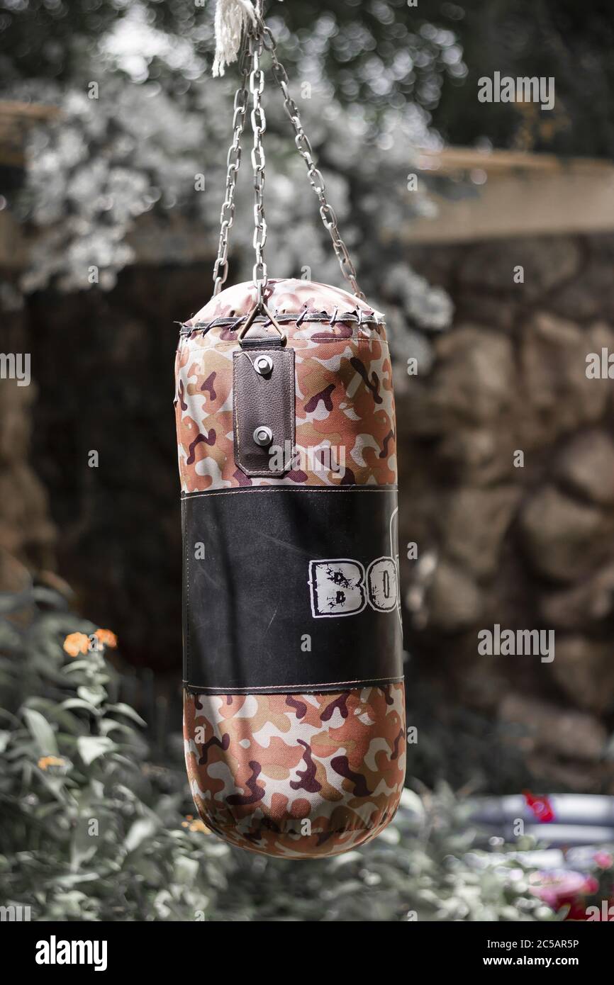 Vertical selective focus shot of a boxing bag hung from chains in a ...