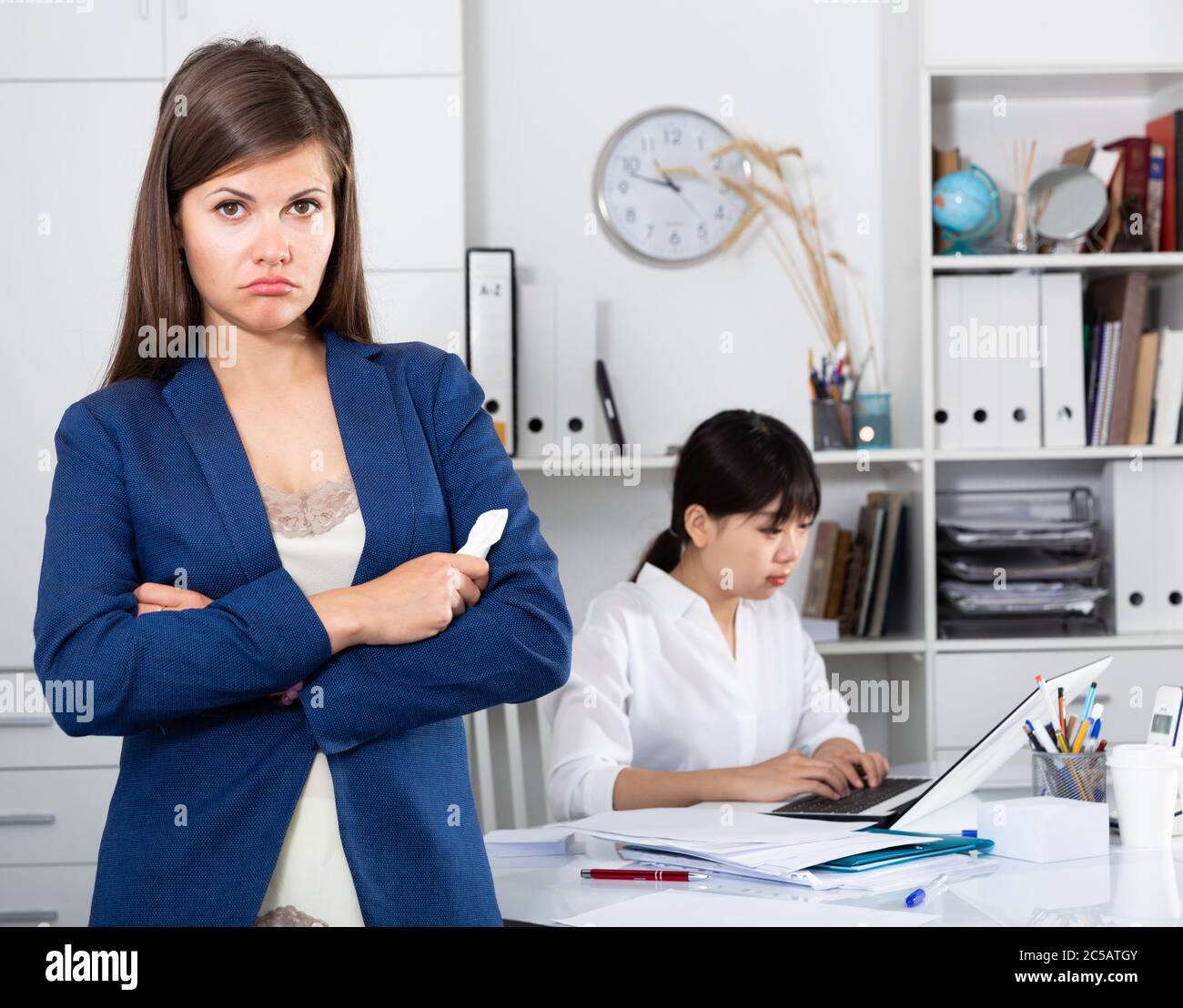 Business woman crying standing in office with working colleague behind ...