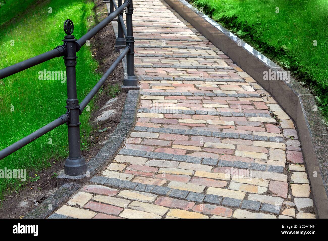 pedestrian walkway made of stone tiles and a granite curb with iron ...