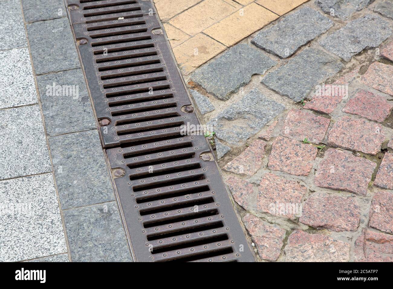drainage grate of a storm system on a pedestrian sidewalk made of stone ...