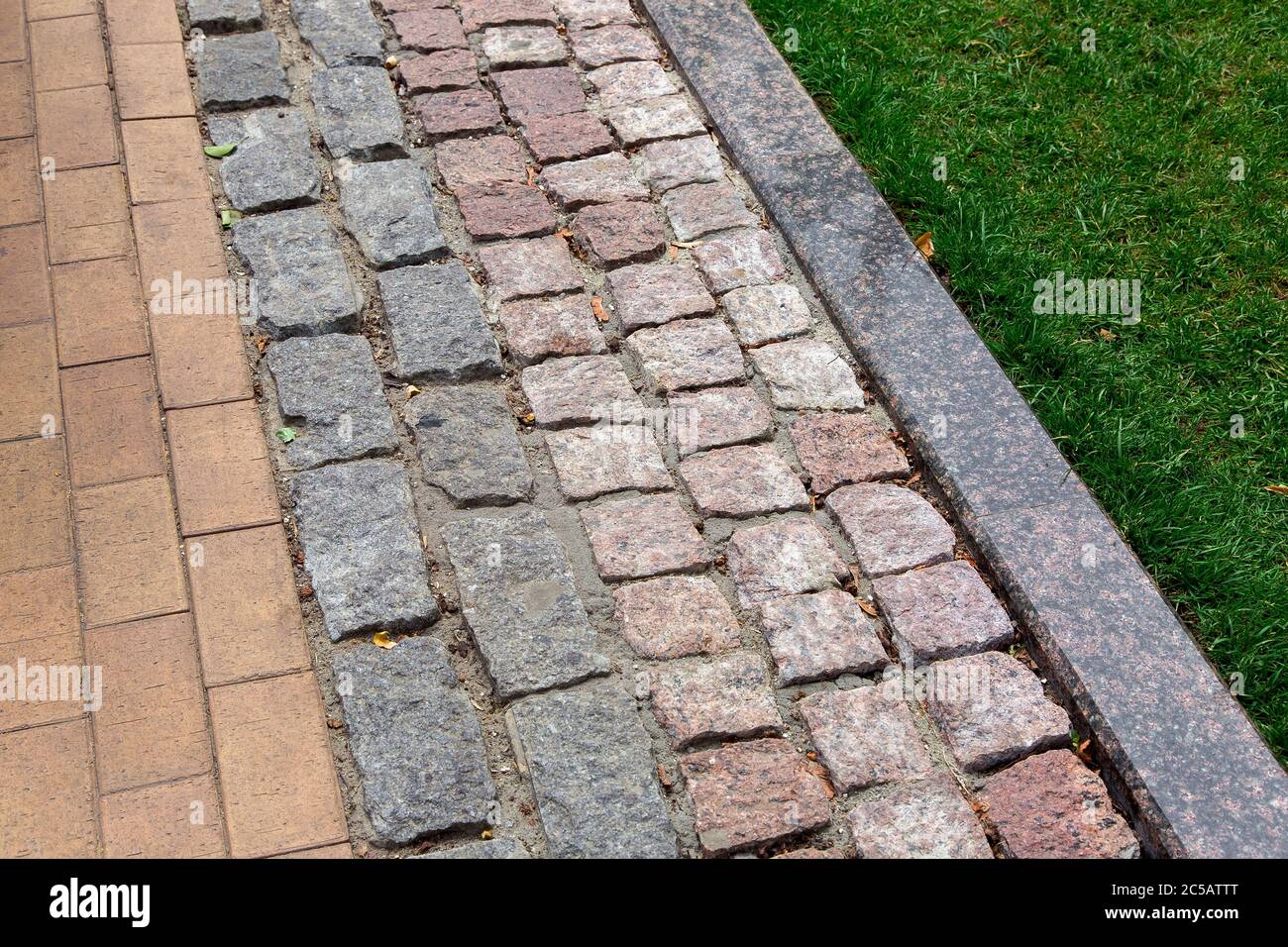 a pedestrian pavement made of stone and granite tiles with a curb near ...