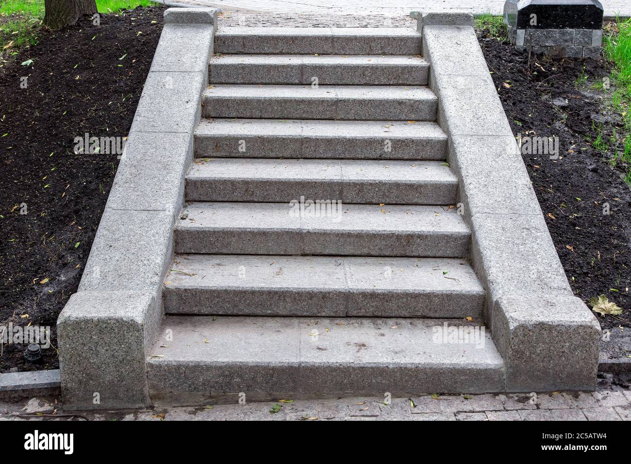 stone steps of gray granite blocks on a slope in a park, front view ...