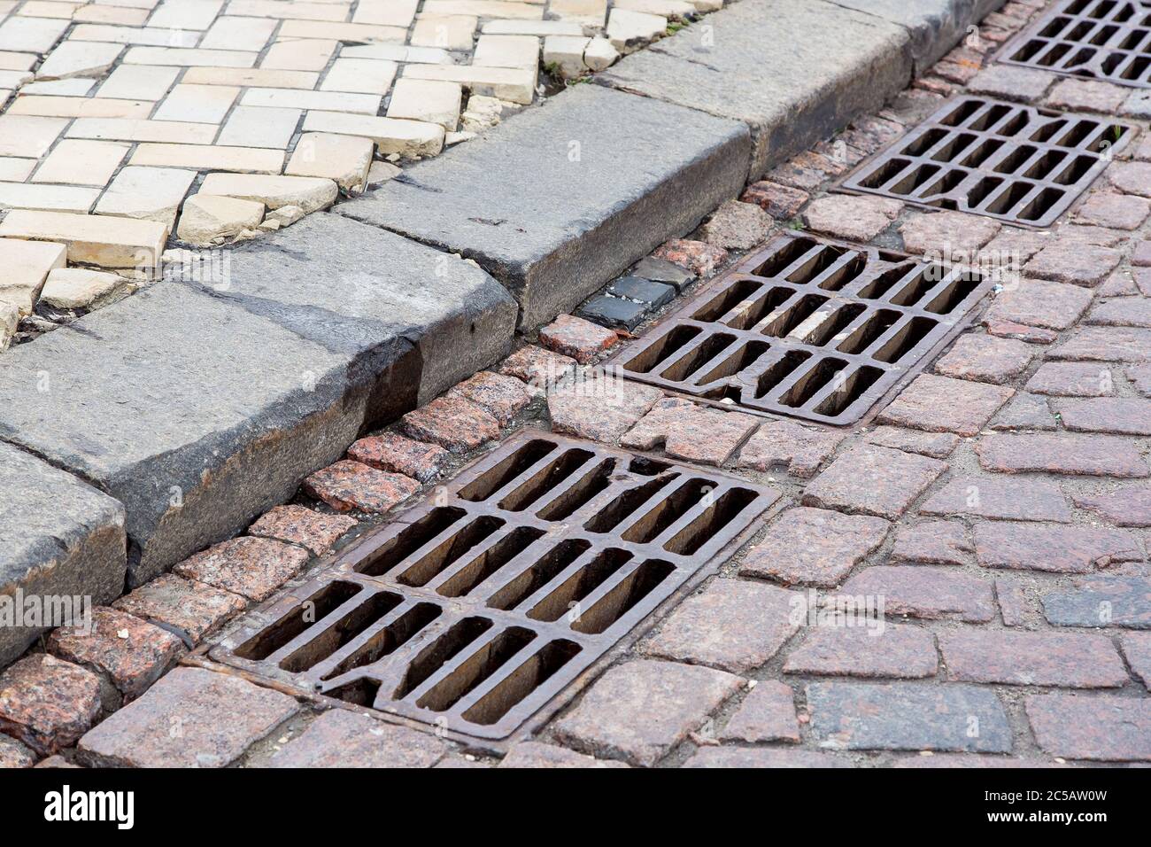 grille of the drainage system manhole on the paving road made of stone ...