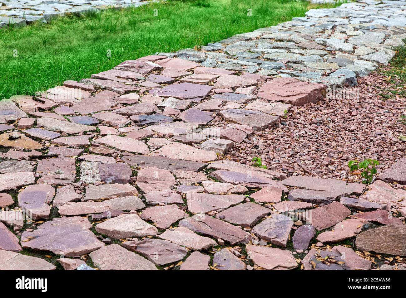 footpaths made of natural rough stone paved with mosaic in the lawn ...