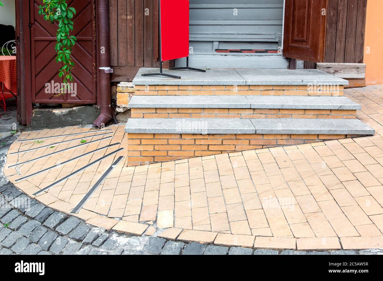 Brick threshold on the slope with granite steps to the open wooden ...