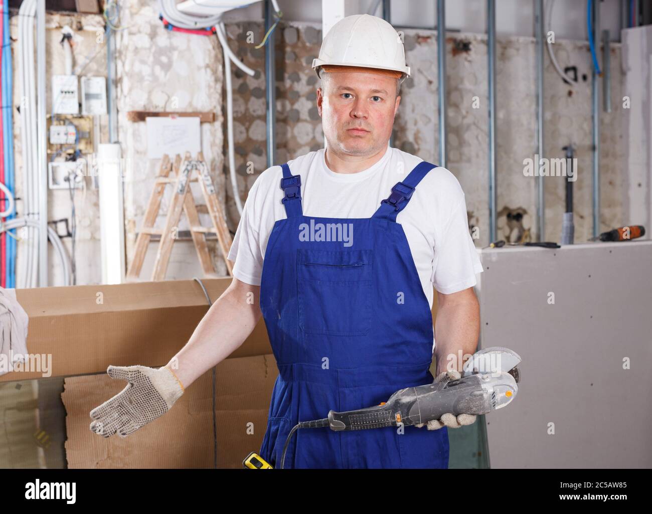Puzzled builder handyman examining room while planning renovation works ...
