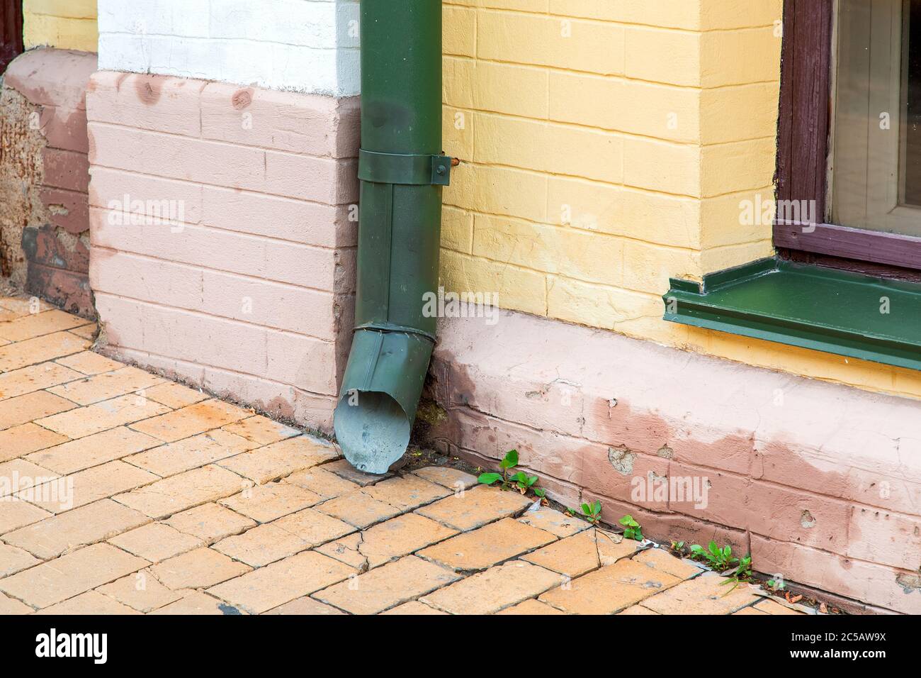 green rain pipe rain system on the facade of the brick house near the ...