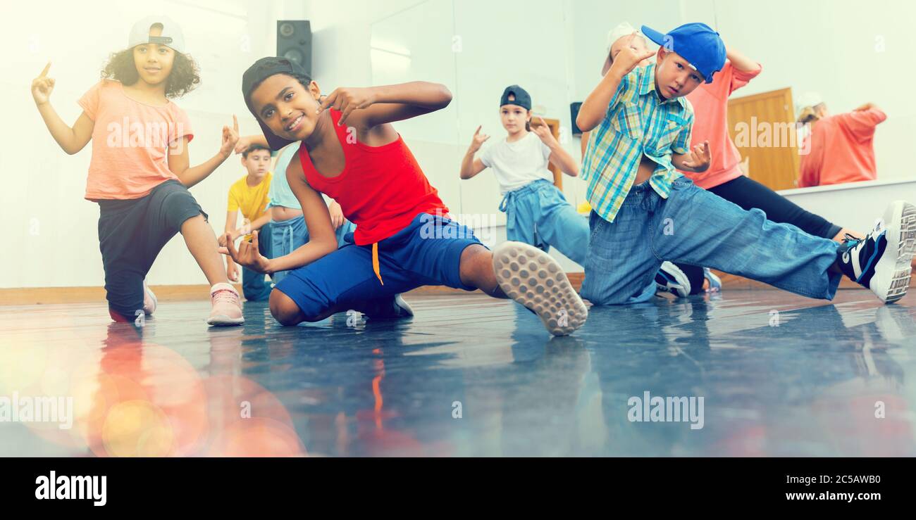 Positive girls and boys with female teacher posing in dance studio ...