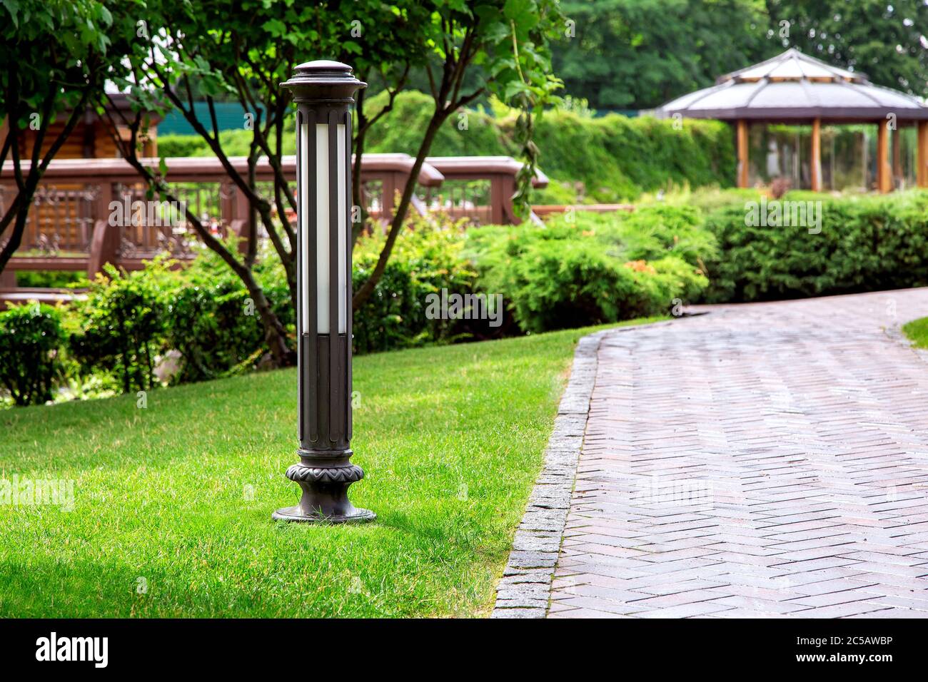 Iron ground lantern mounted in the green lawn of the backyard with ...