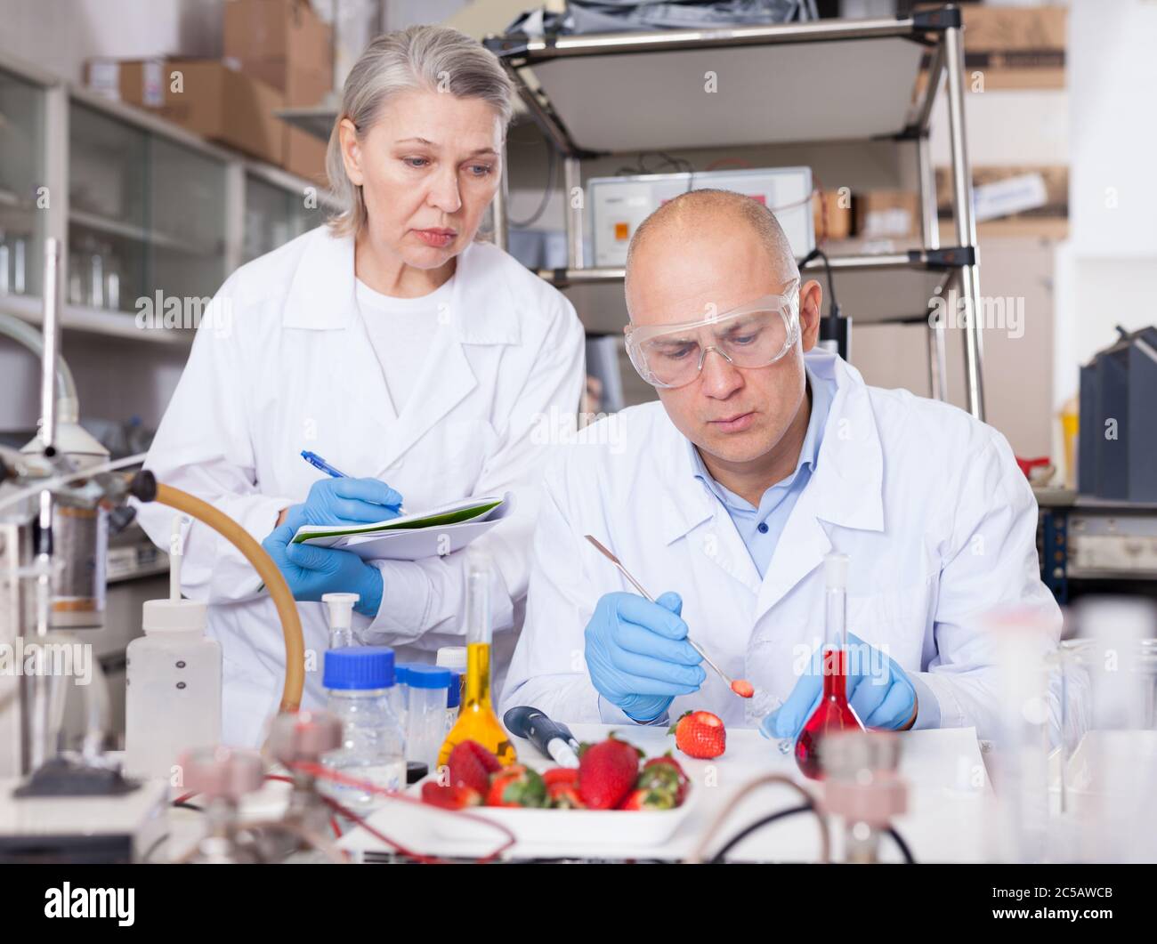 Two professional genetic scientists working in laboratory, taking notes ...