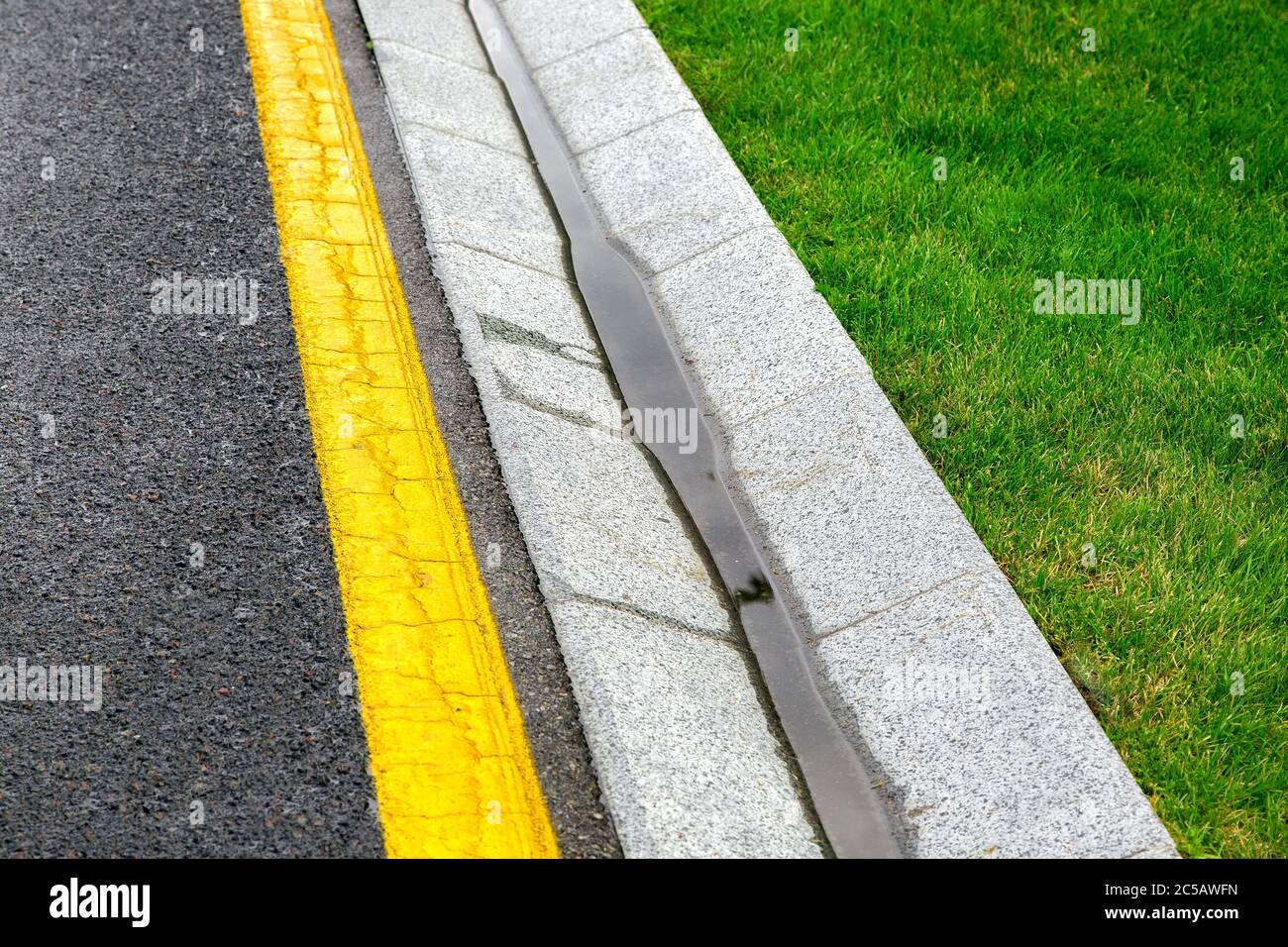 roadside drainage system tray with flowing rain water on an asphalt ...