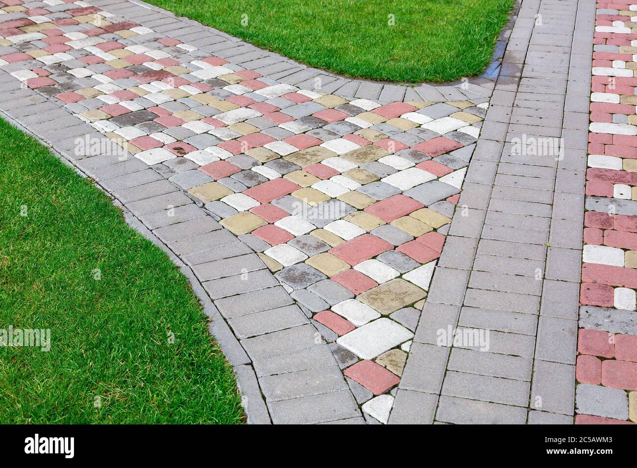 Tile path intersection angle in a park with a green lawn on a summer ...