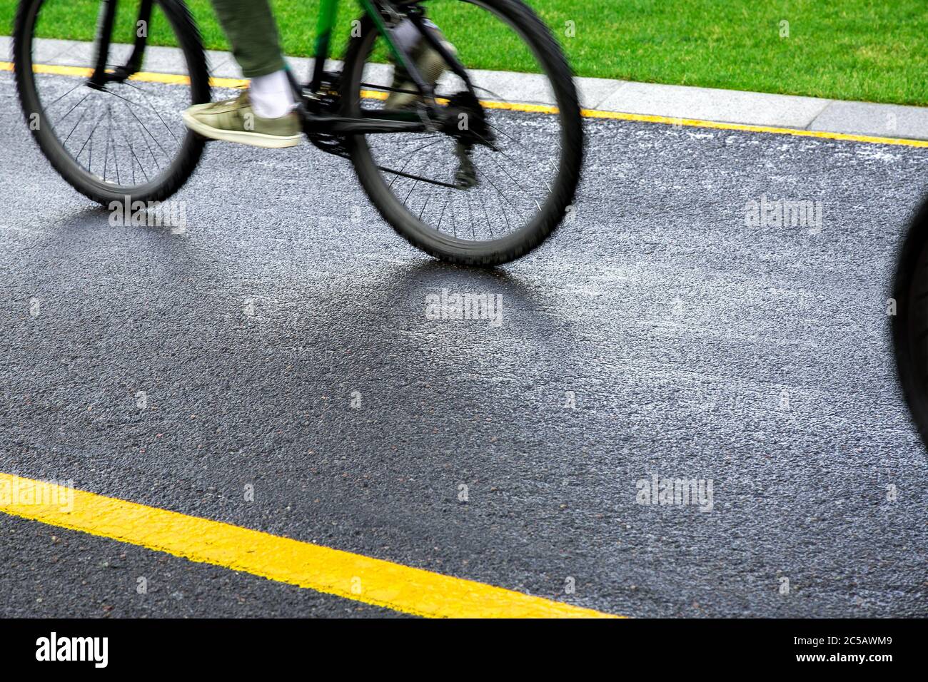 asphalt bike path wet after rain with yellow markings with a passing ...