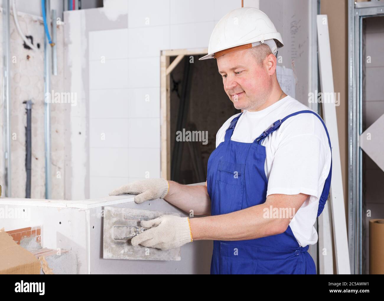 Professional plasterer taping drywall joints with spatula and plaster ...