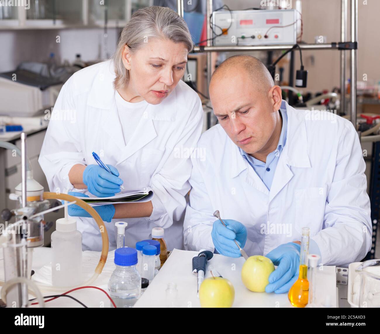 Two professional genetic scientists working in laboratory, taking notes ...