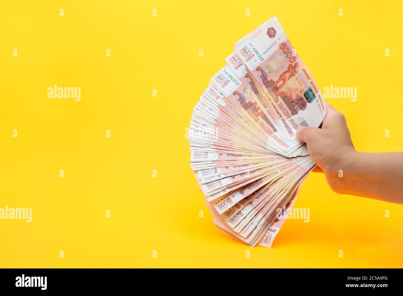 Hand holds a fan from a pack of five thousandth Russian bills on a ...