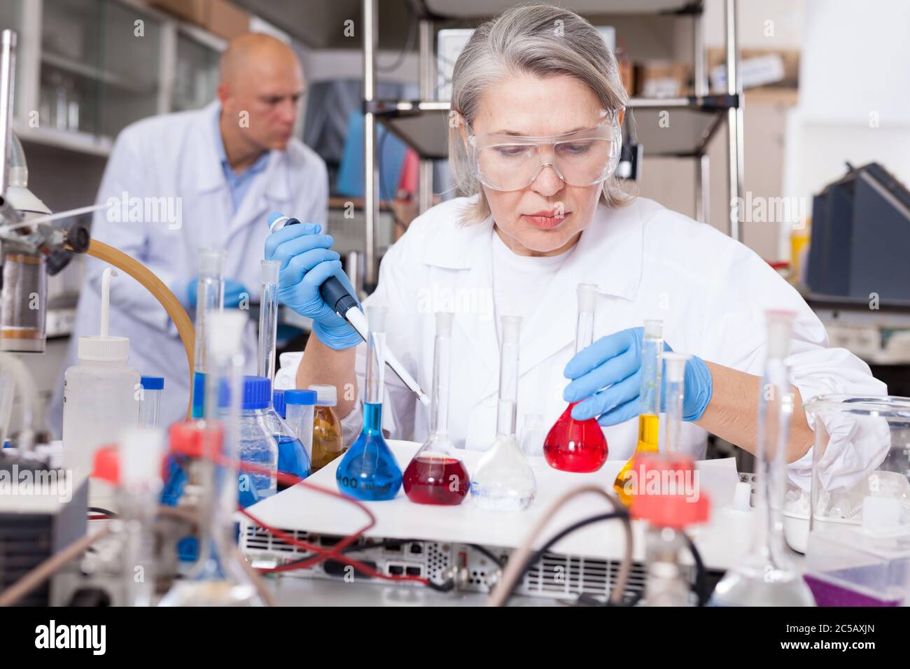 Experienced female biochemists mixing chemicals while performing ...