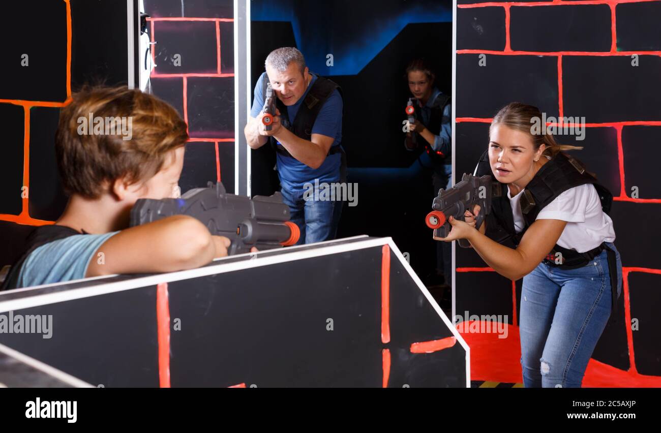 Modern parents and children with laser pistols playing laser tag in ...