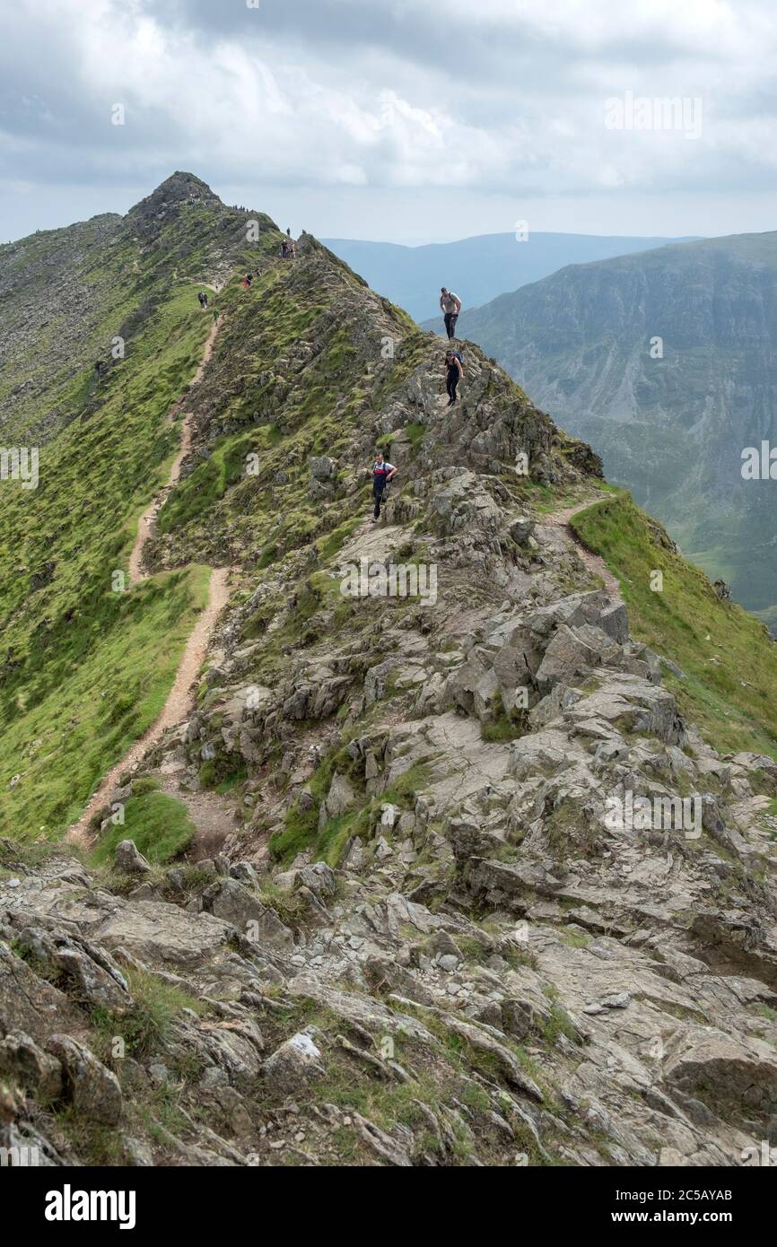 Walkers scramble over rocks on the ridge of striding edge in the lake ...