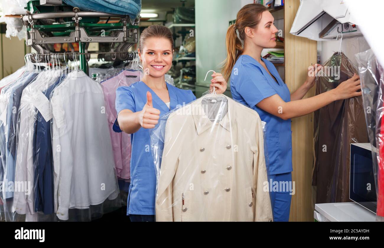 Two confident smiling female workers offering professional dry cleaning ...