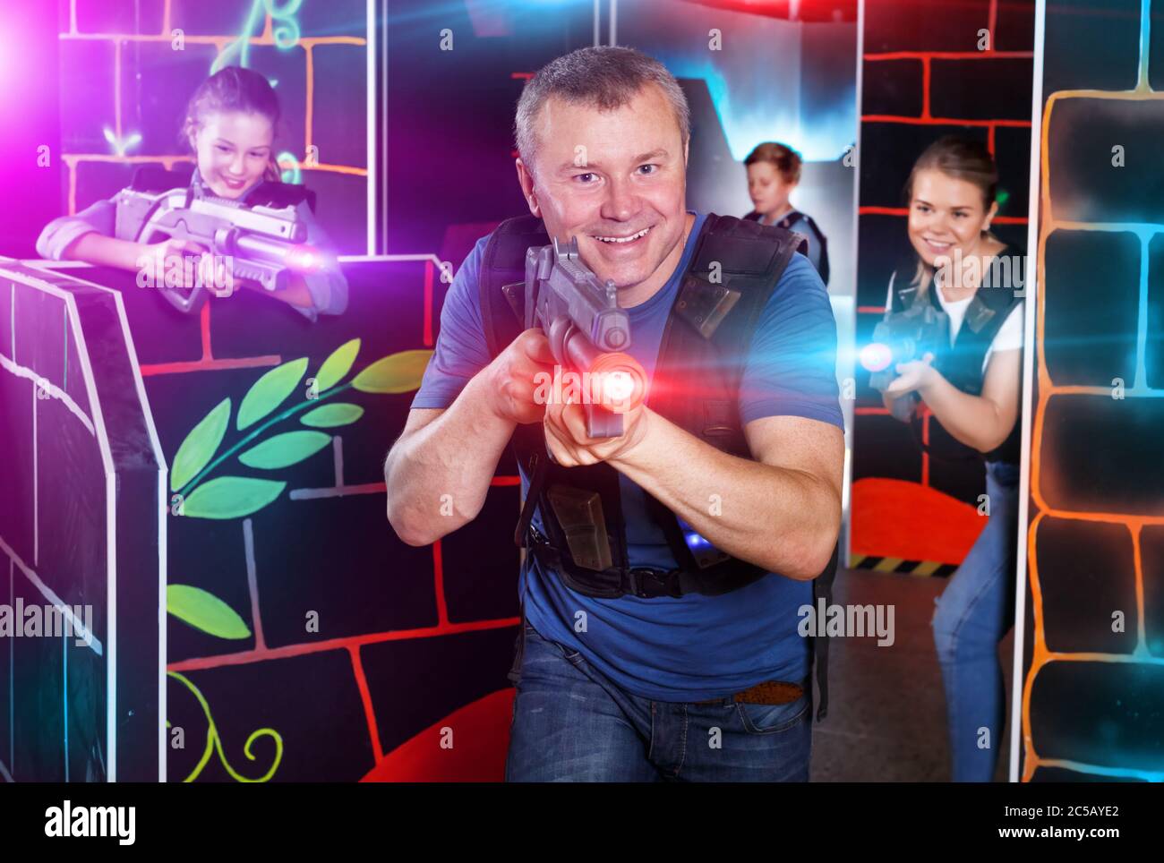 Emotional man with laser pistol playing laser tag with his family in ...