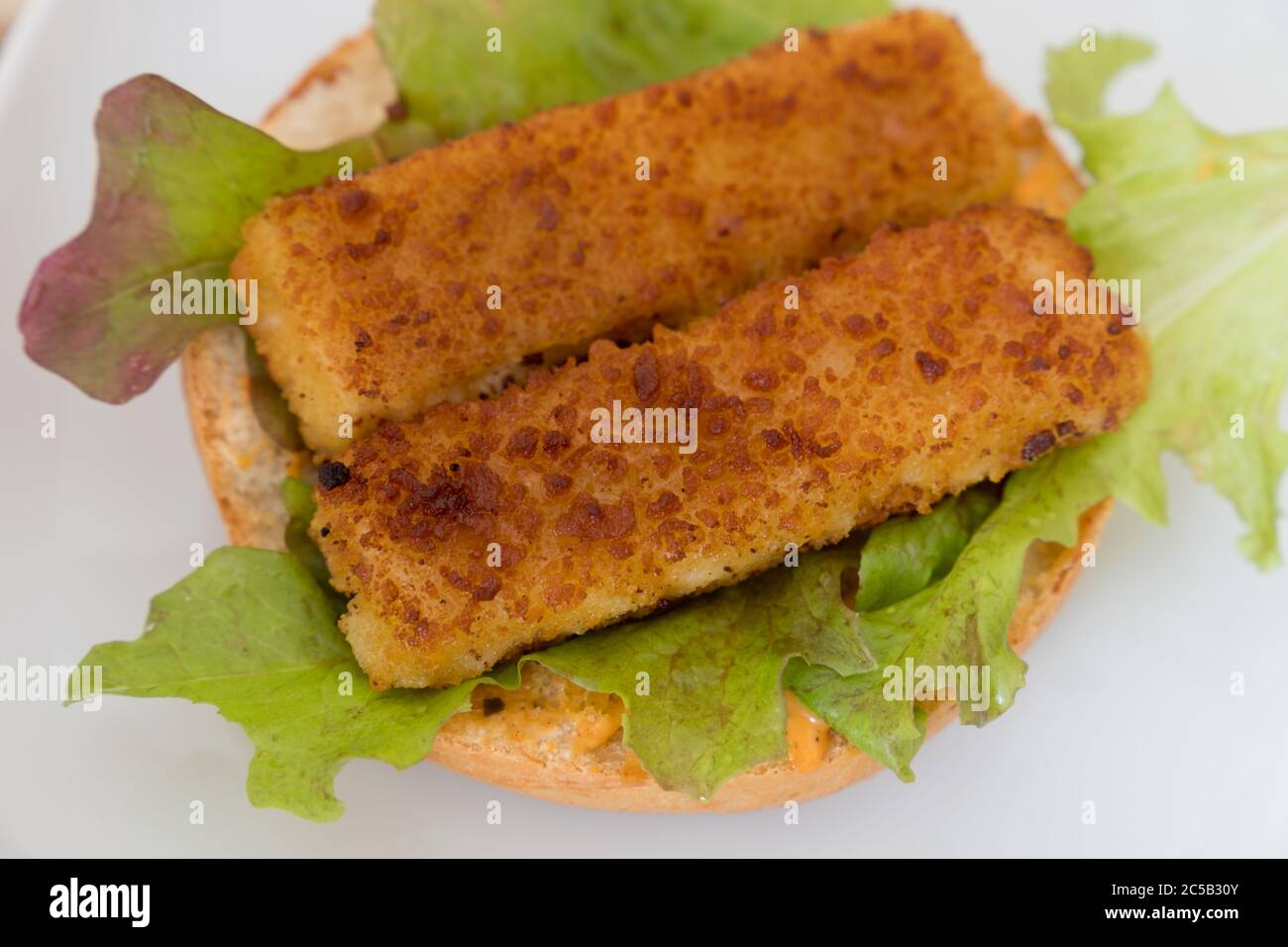two fried fish sticks with salad on a bun Stock Photo - Alamy