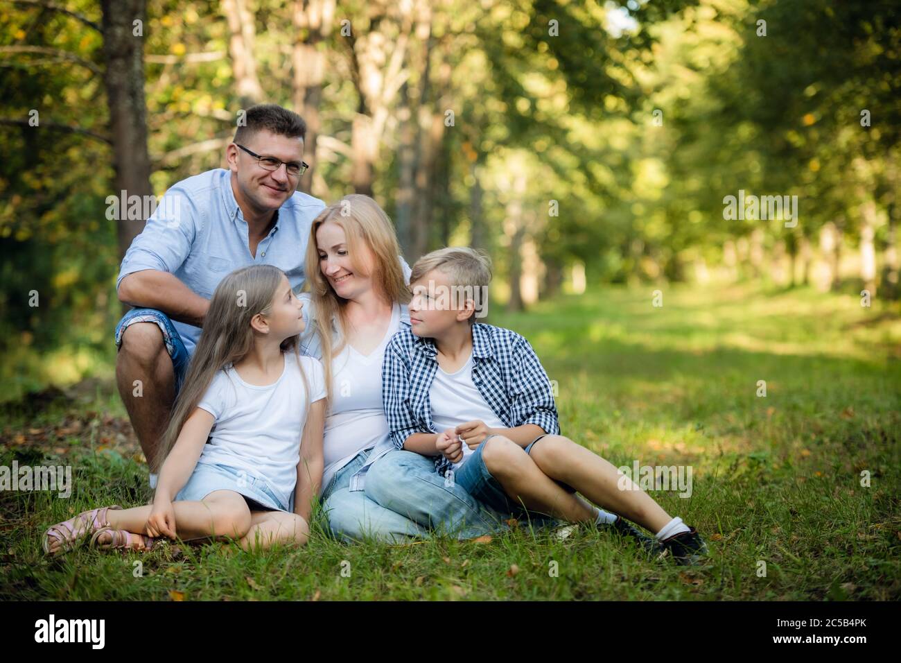 Happy family outdoors smiling in a summer forest Stock Photo - Alamy
