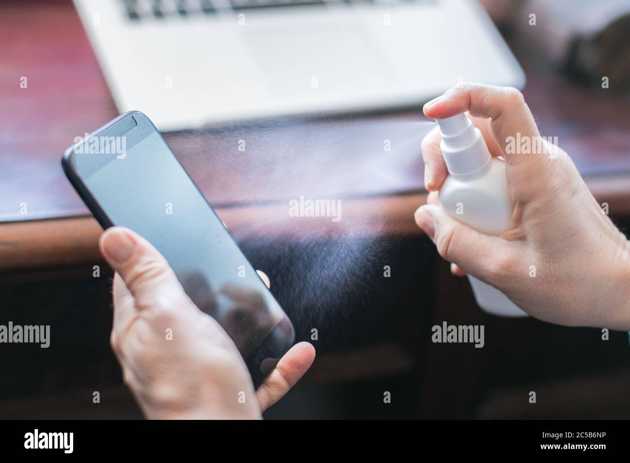 sanitizing cell phone with alcohol spray Stock Photo - Alamy