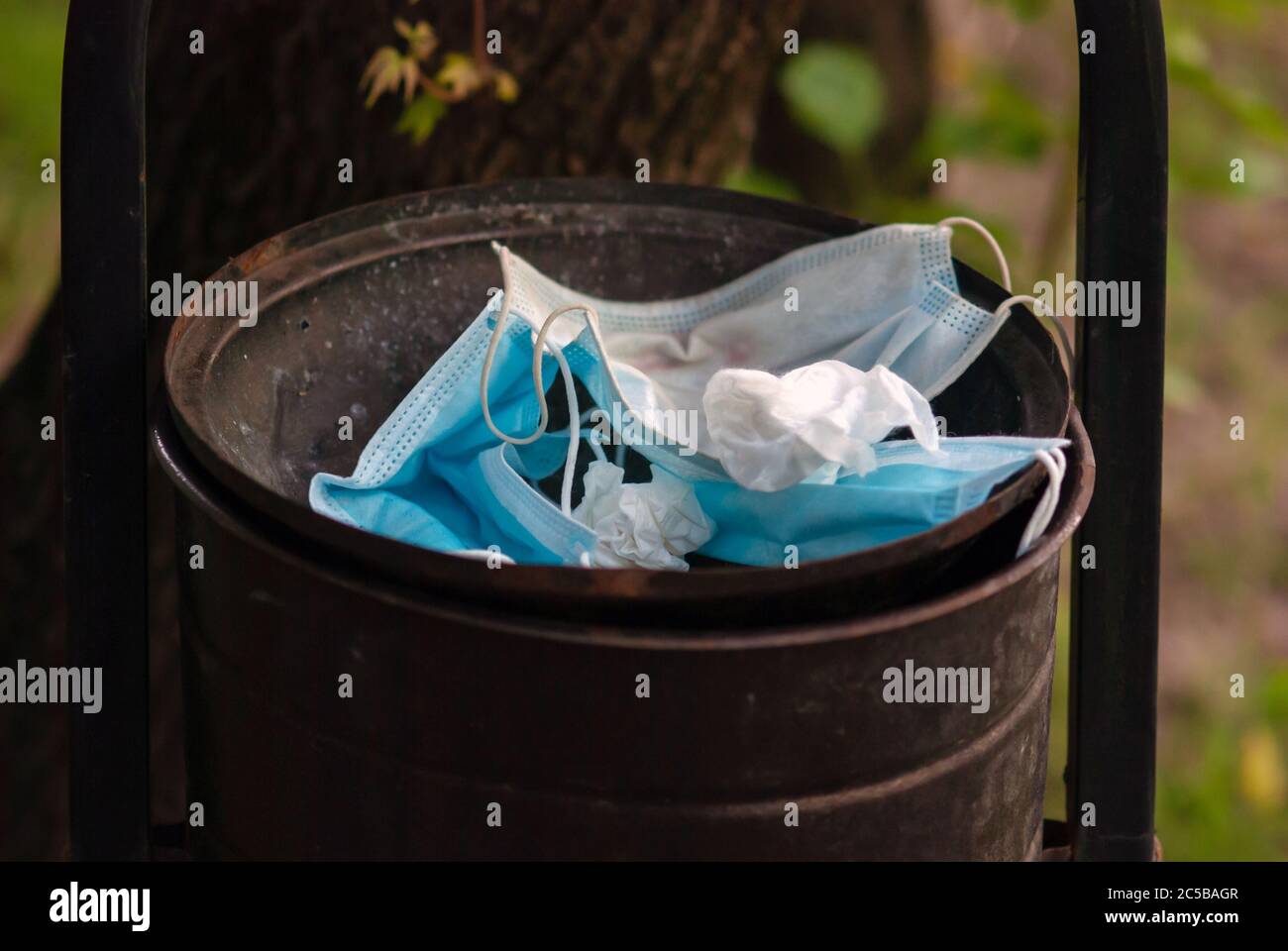face masks and used antibacterial wipes thrown into trash bin outdoors ...