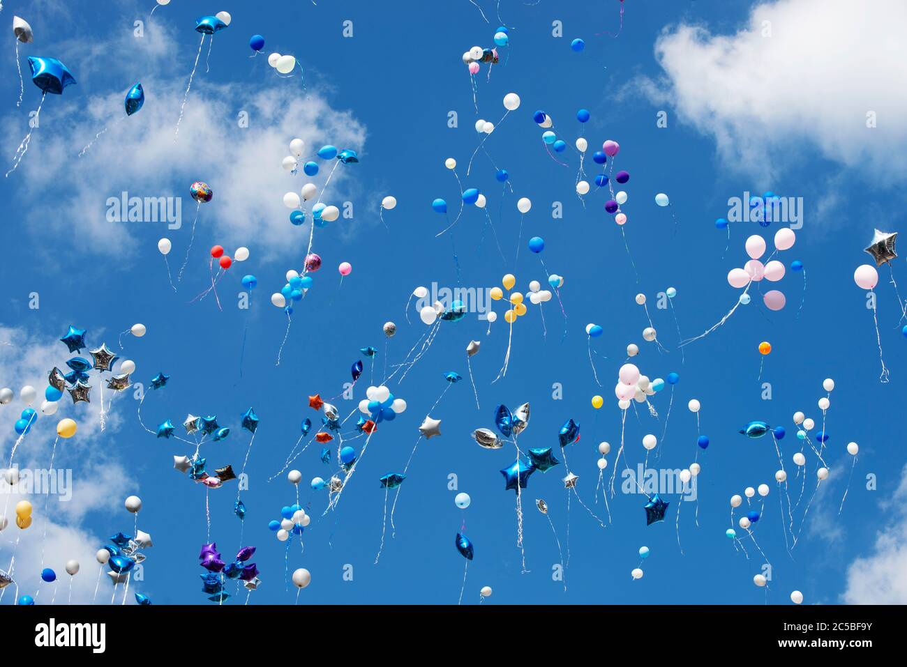 Balloons float in a blue and partially cloudy sky Stock Photo - Alamy
