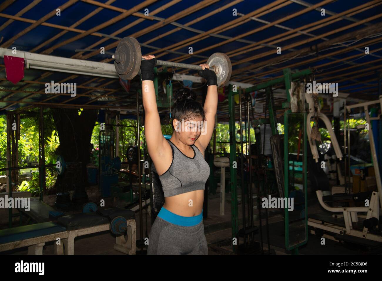 Asian young fitness woman lifting a weight in the gym. Fitness woman ...