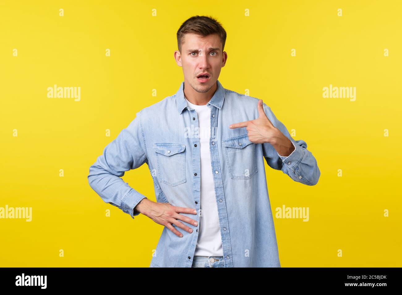 Insulted caucasian blond man in casual clothes, pointing at himself ...
