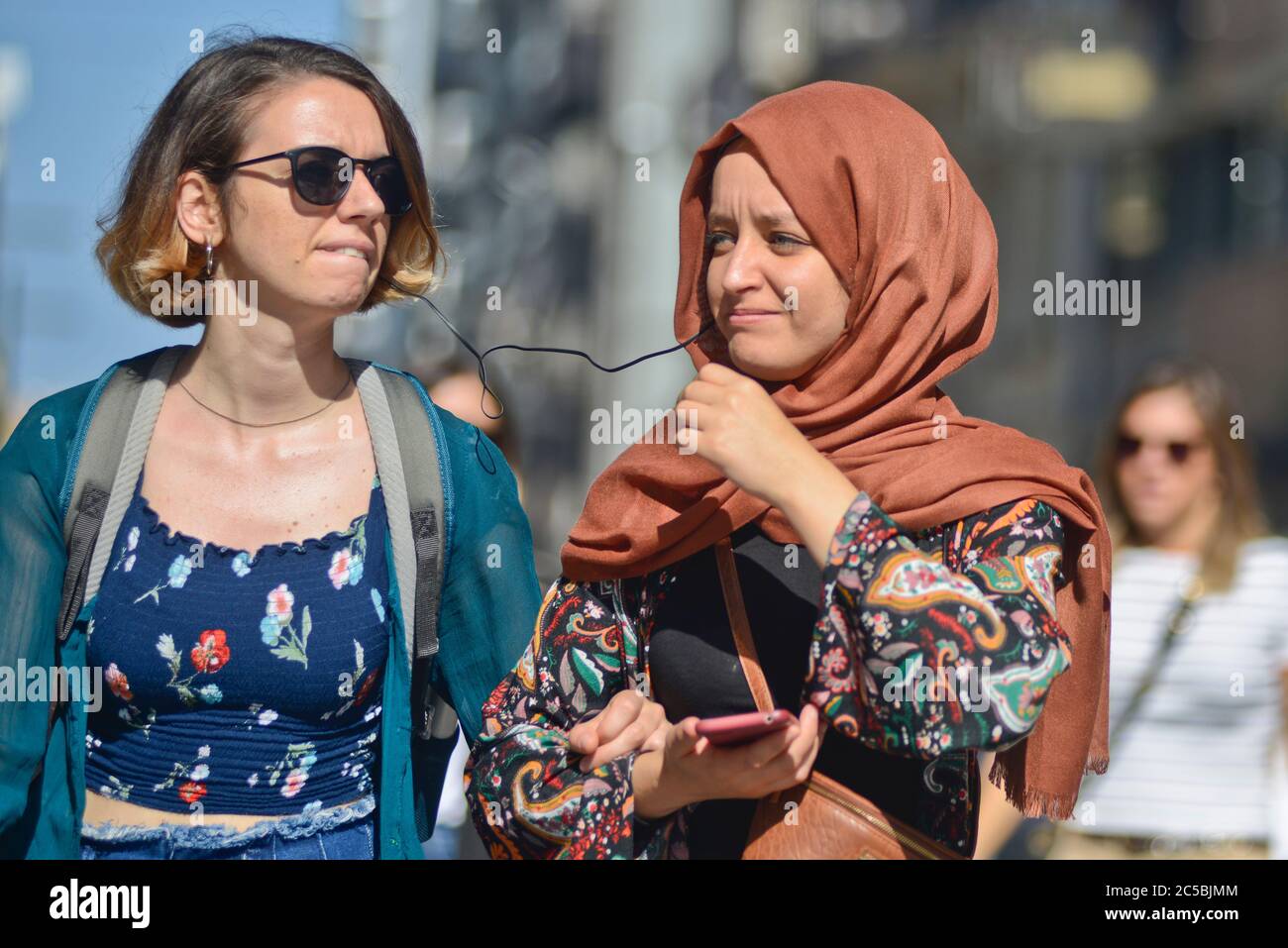 Italian young girls, one of them muslim, listening music togheter while ...